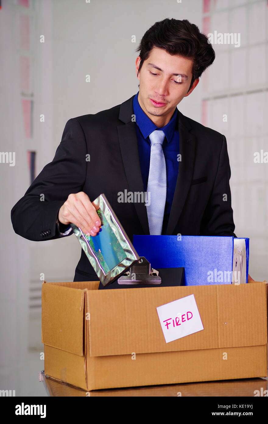 Close up of sad man packing his belongings after being fired from his ...