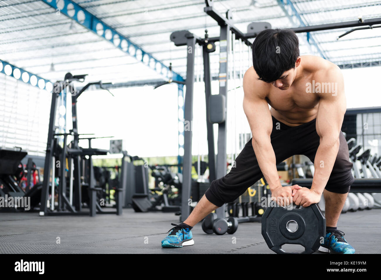young man bodybuilder execute exercise in fitness center. male athlete ...