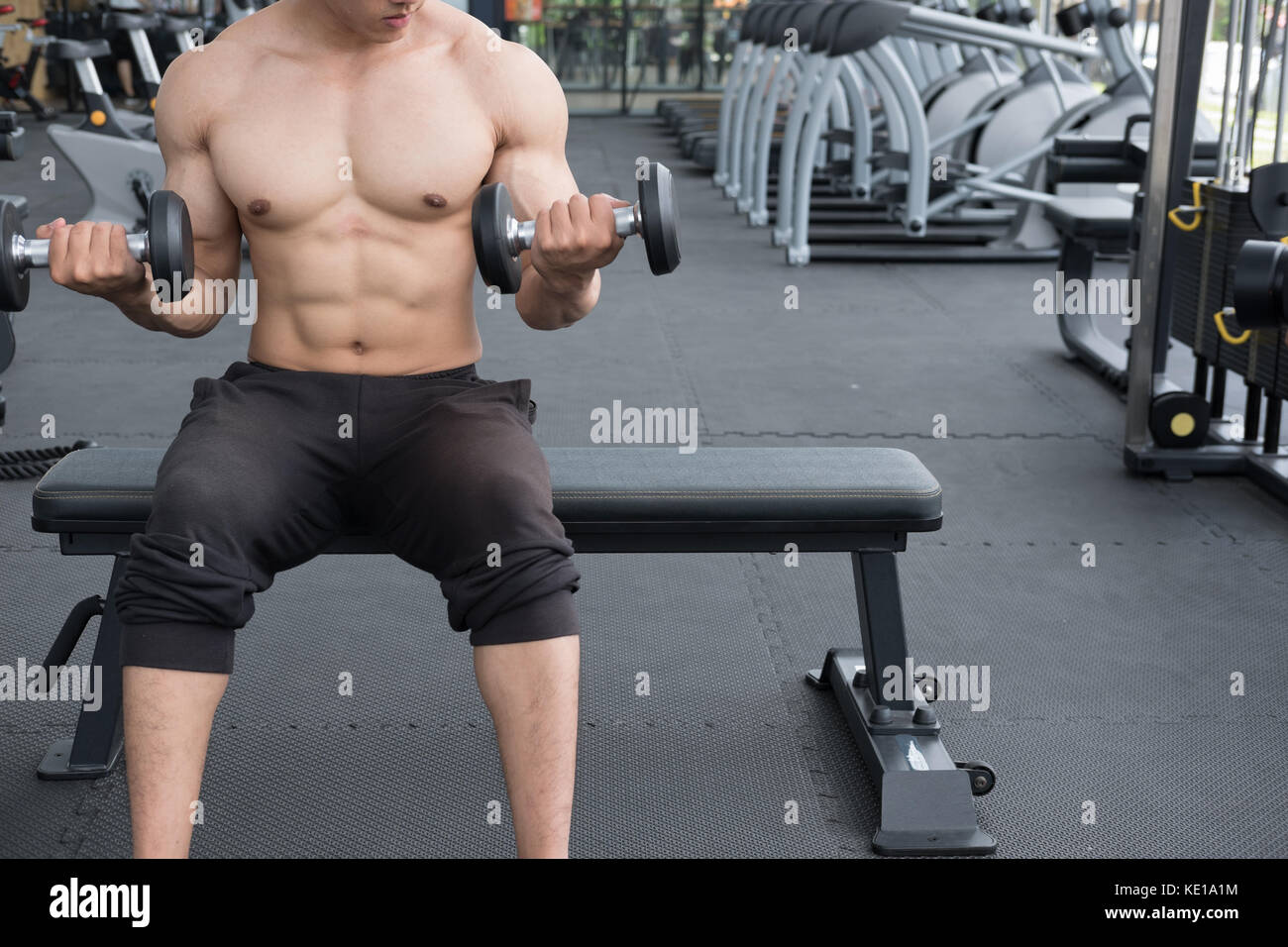 young man lift dumbbell in gym. bodybuilder male working out in fitness ...