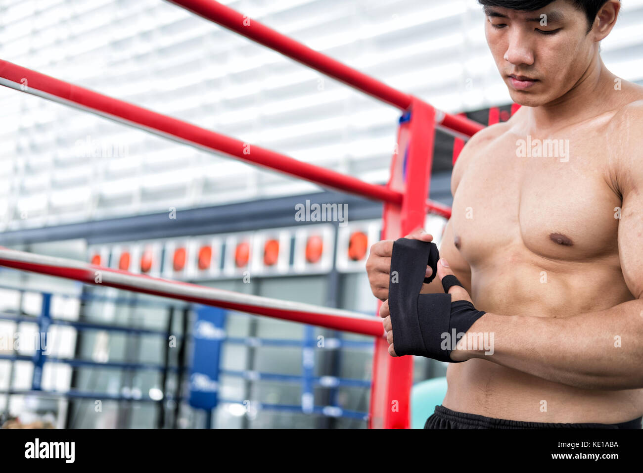 young male fighter wear bandages on fist. muscular man bind bandage on ...