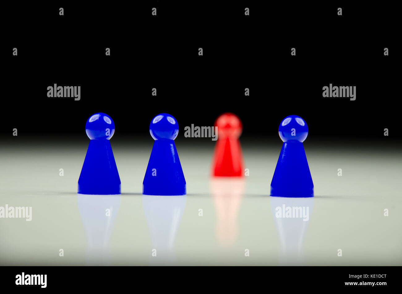 A close-up view of a row of blue figures and one red figurine unfocused ...