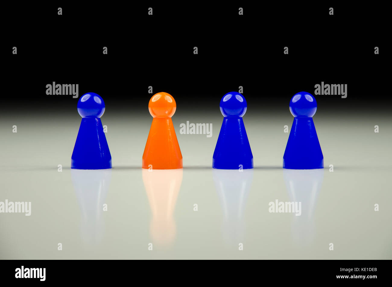 Close-up view of a row of blue figures with one red on a blurred white ...