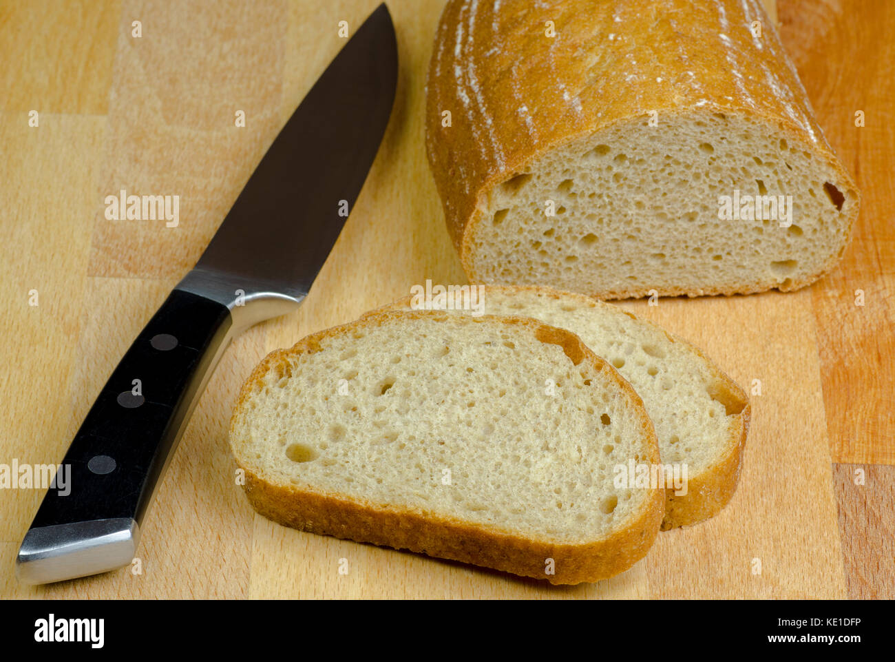 Close-up photo of two slices of bread cut by knife with black handle on ...