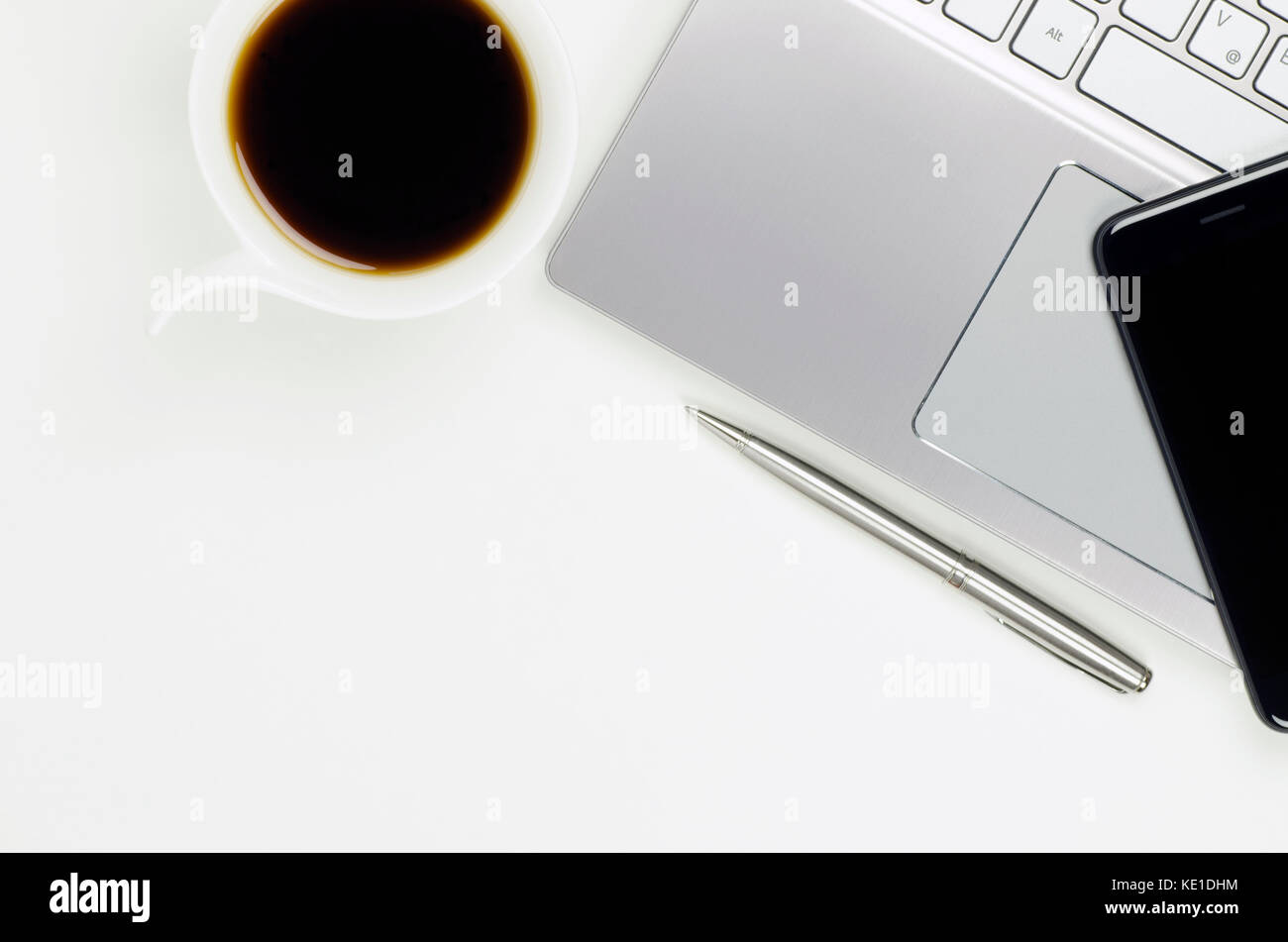 Close-up view of still life with laptop, smatter and pen next to a cup ...