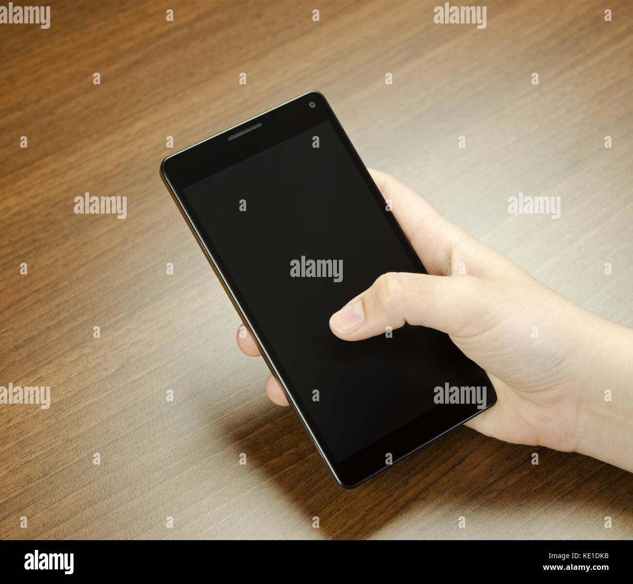 Closeup view of a hand with fingers holding a black cell phone with ...
