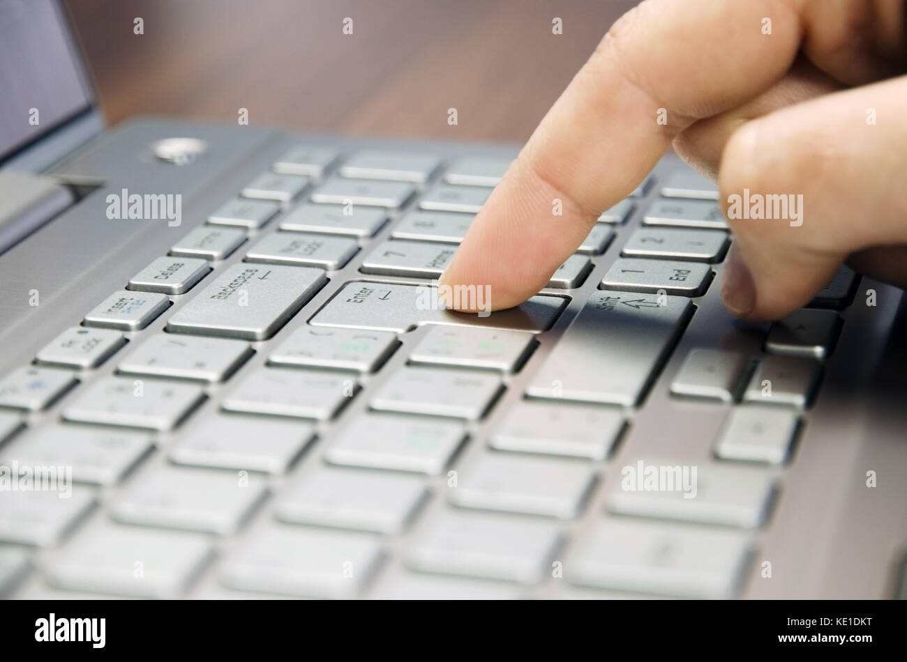 Closeup view of a hand with a finger press the Enter key on the silver ...