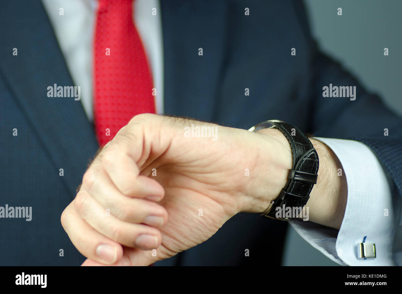 Close-up view of manager in suit and red tie looking at watch Stock ...