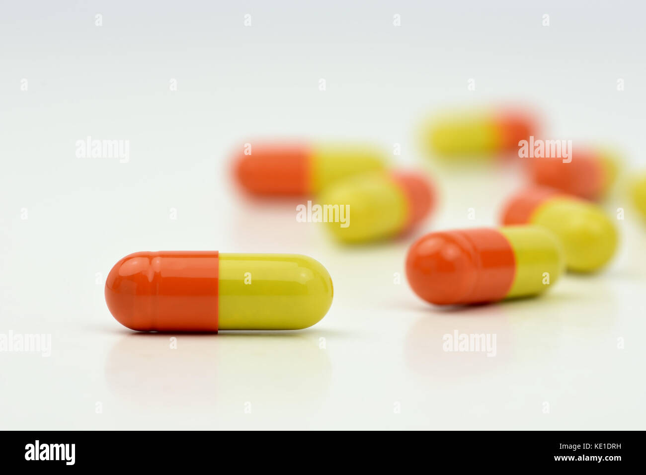 Close-up photo of yellow orange pills isolated on white background with ...