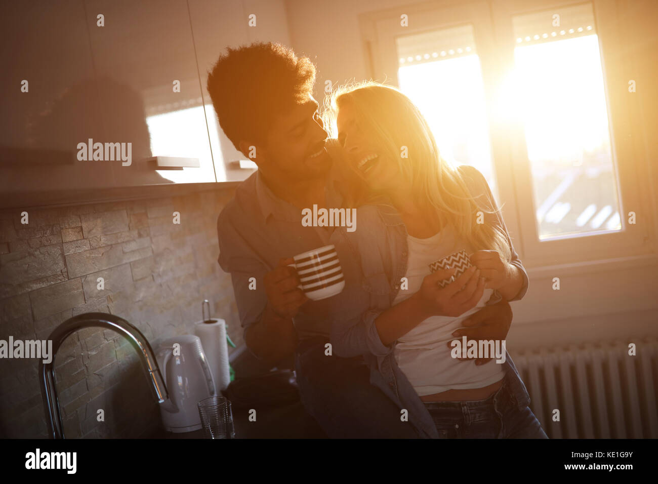 Beautiful young couple hugging and drinking coffee in kitchen Stock ...