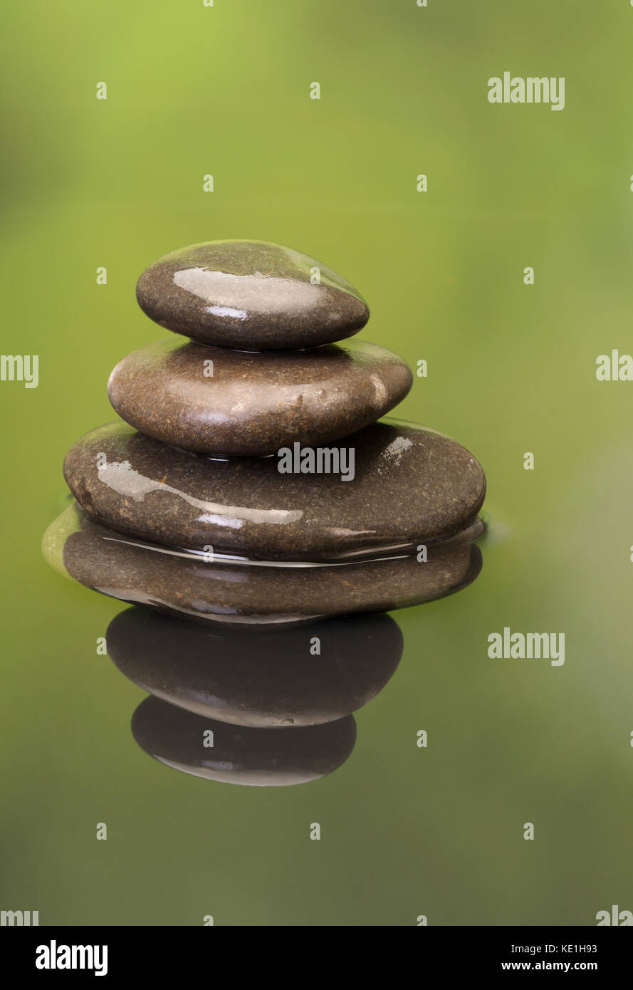 Stacked zen boulders reflected in green water Stock Photo - Alamy