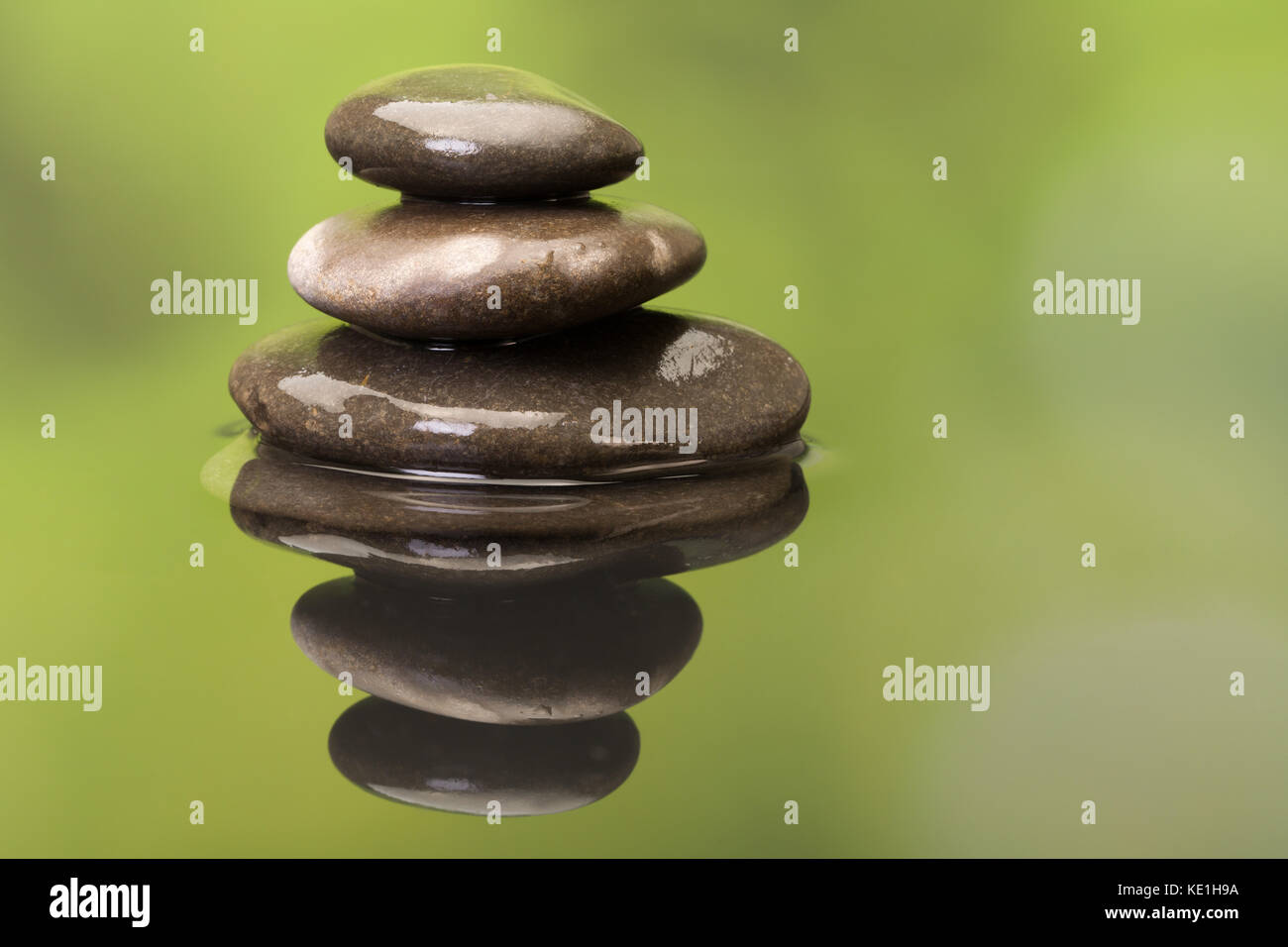 Stacked zen boulders reflected in green water Stock Photo - Alamy