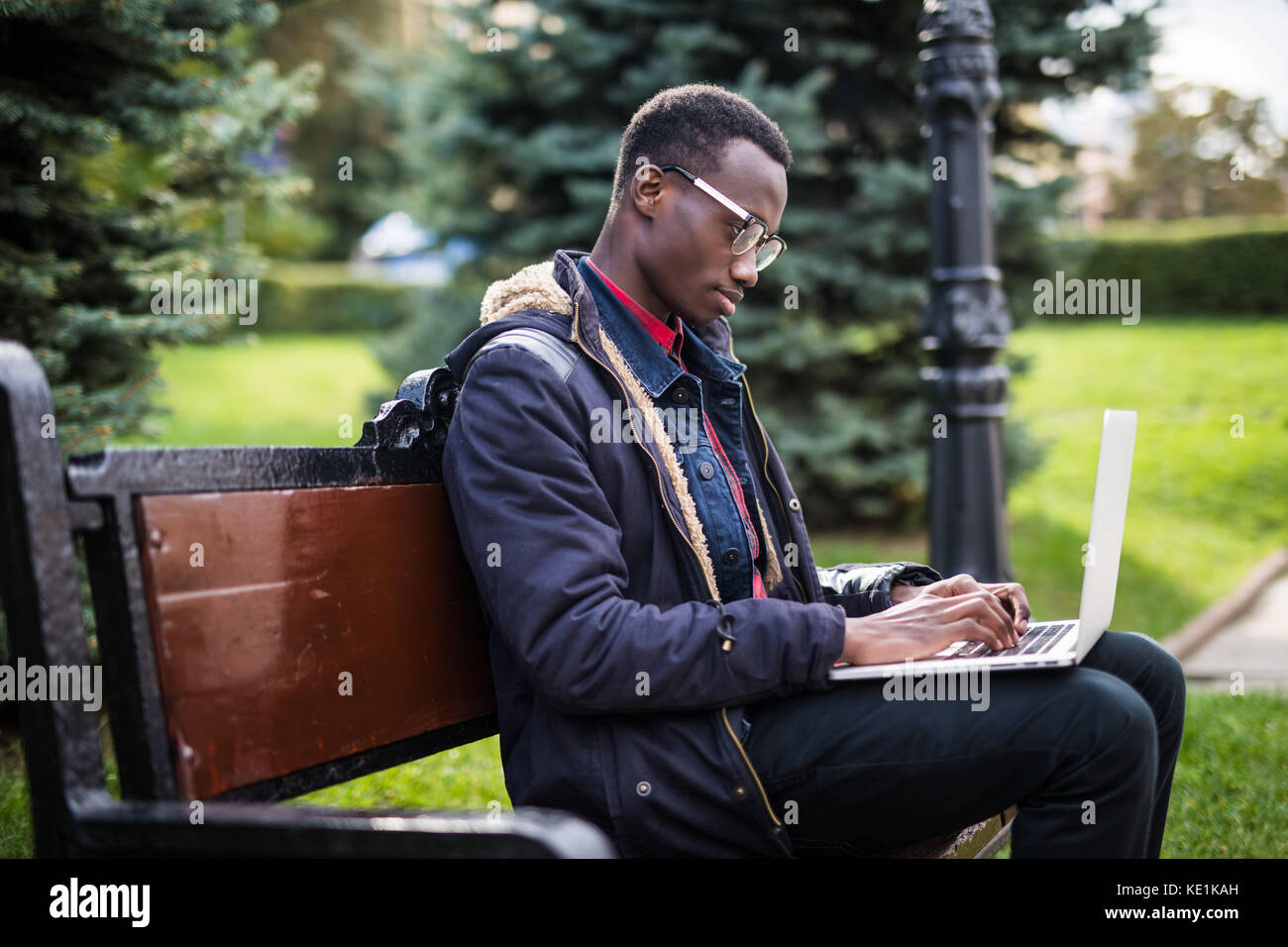Joyful African man using computer outdoors on the bench Stock Photo - Alamy