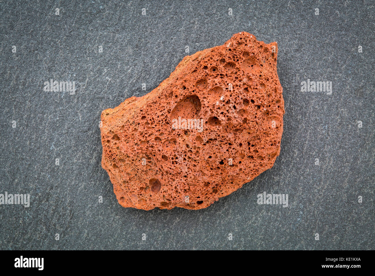 scoria igneous rock sample against gray slate stone, extrusive rock ...