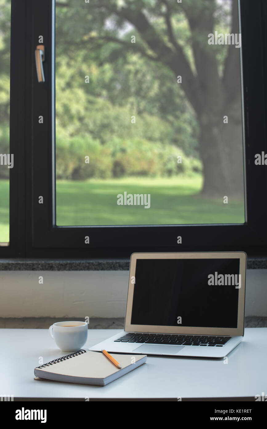 Laptop computer, notepad with pencil and cup of coffee on white desk in ...
