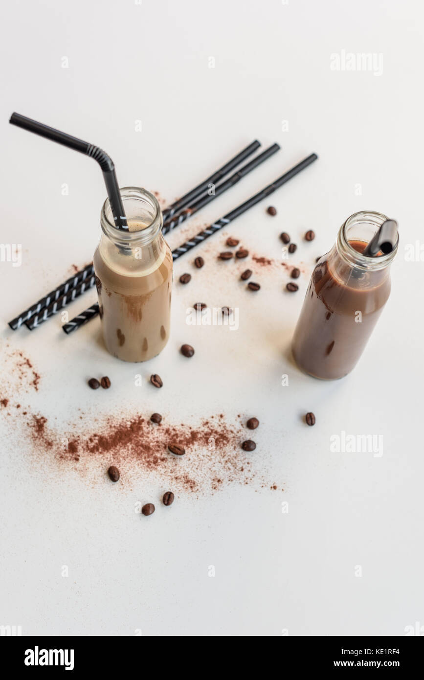Two glass bottles with cold coffee cocktails and straws, coffee beans ...