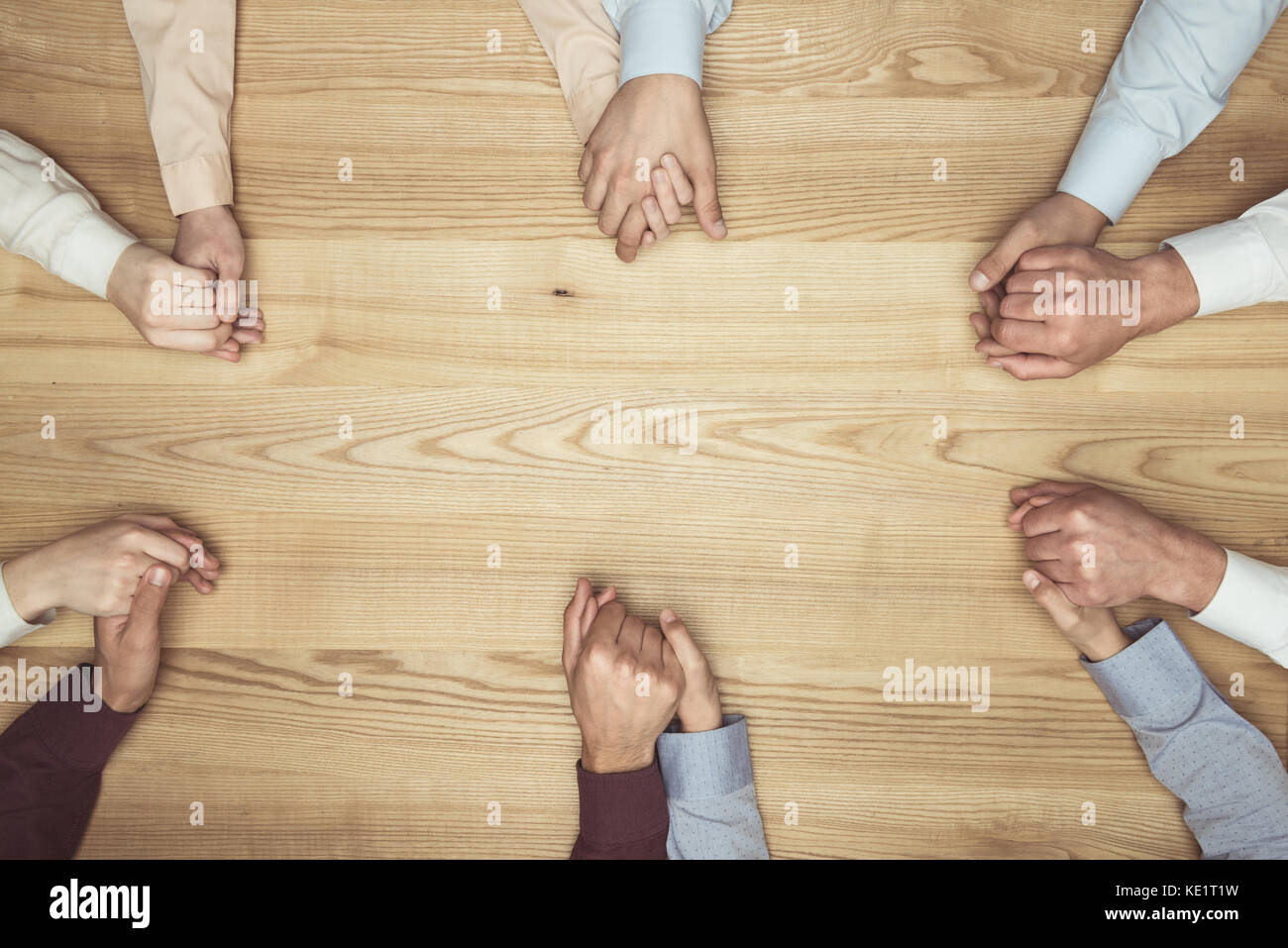 top view of people holding hands on wooden tabletop Stock Photo - Alamy