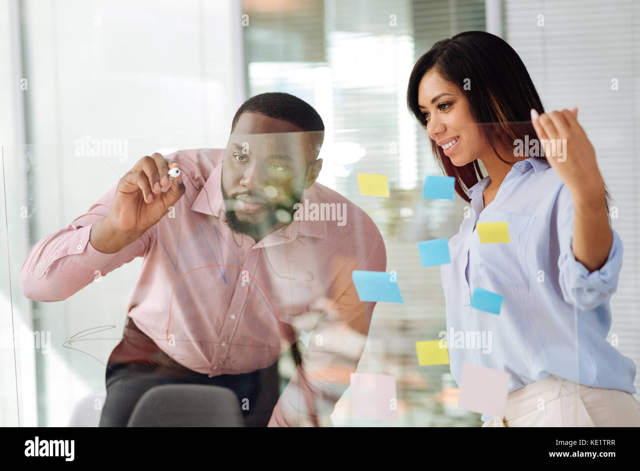 Attentive man drawing scheme on glass board Stock Photo - Alamy