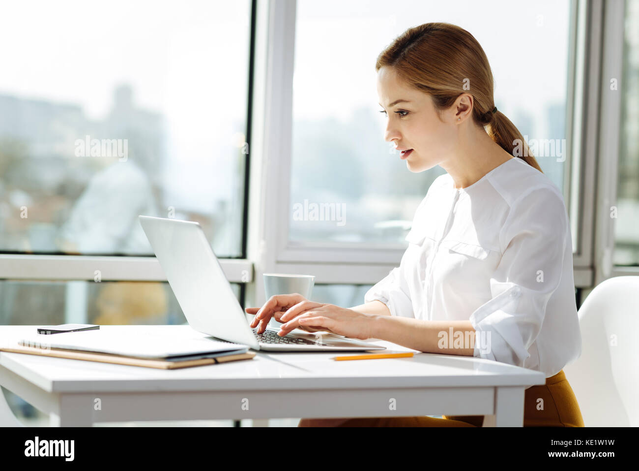 Serious office worker looking at her computer Stock Photo - Alamy