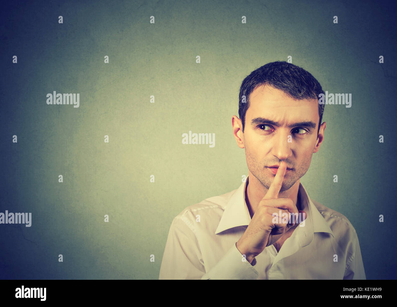 young suspicious man giving Shhhh quiet, silence, secret gesture ...