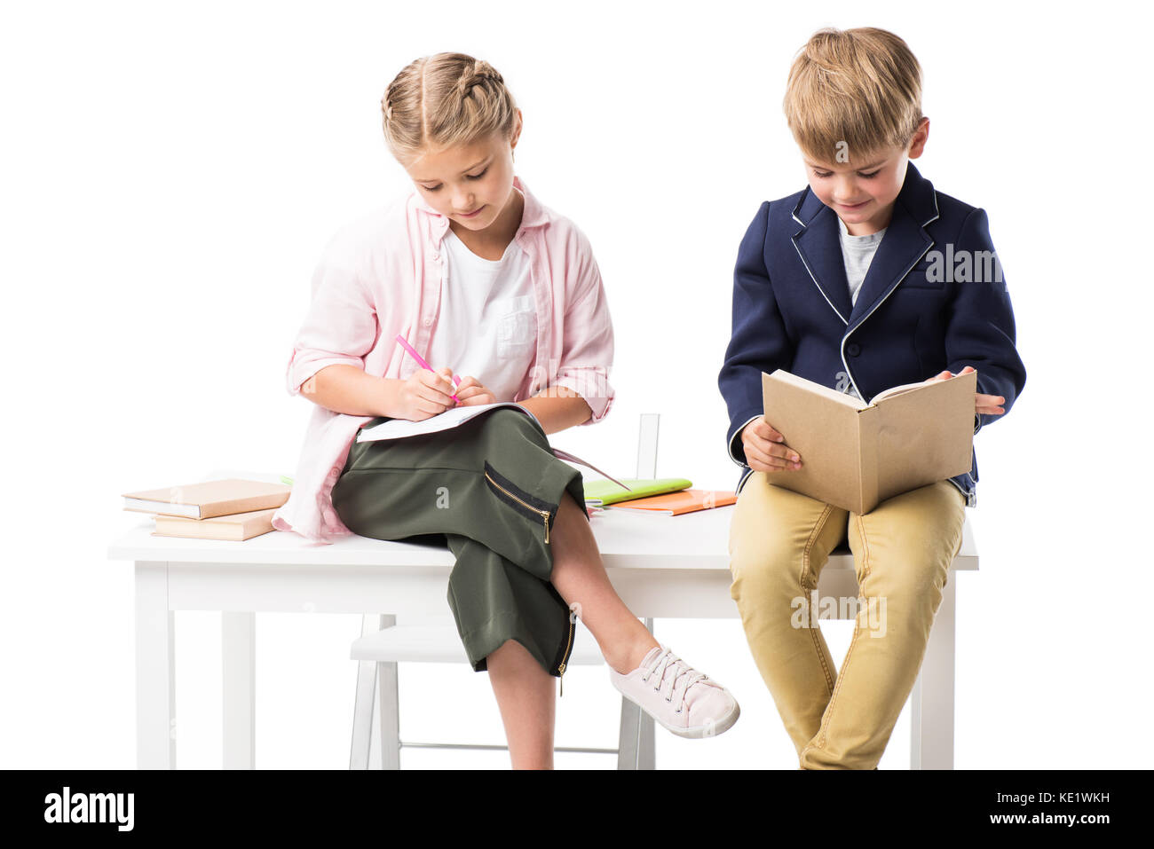cute little children studying while sitting on table isolated on white ...