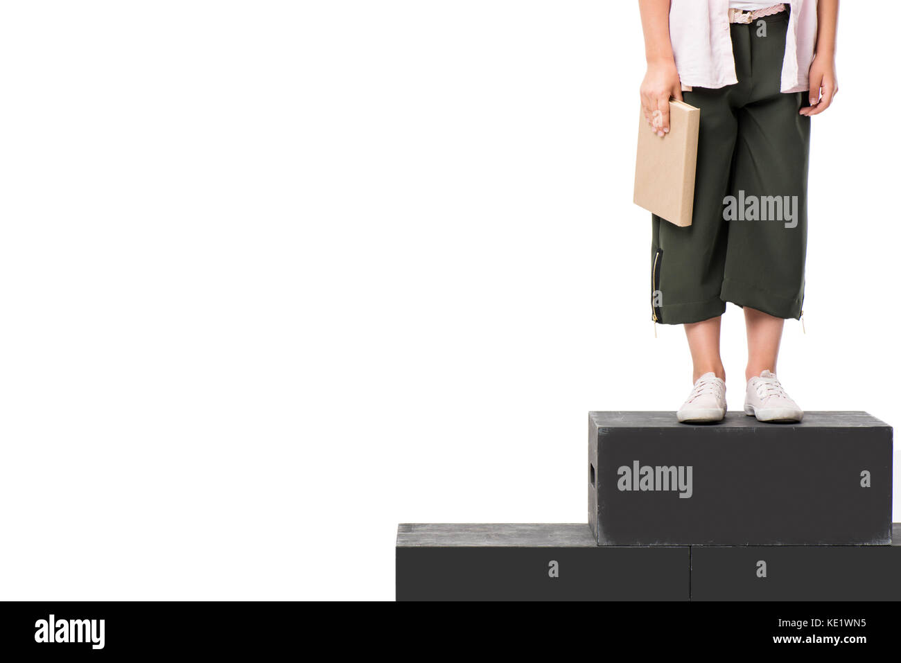 cropped shot of schoolchild holding book standing on podium isolated on ...