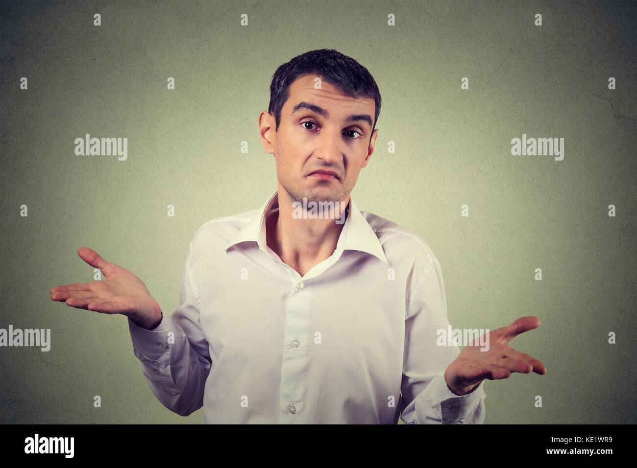 Closeup portrait young upset man shrugging shoulders who cares so what ...