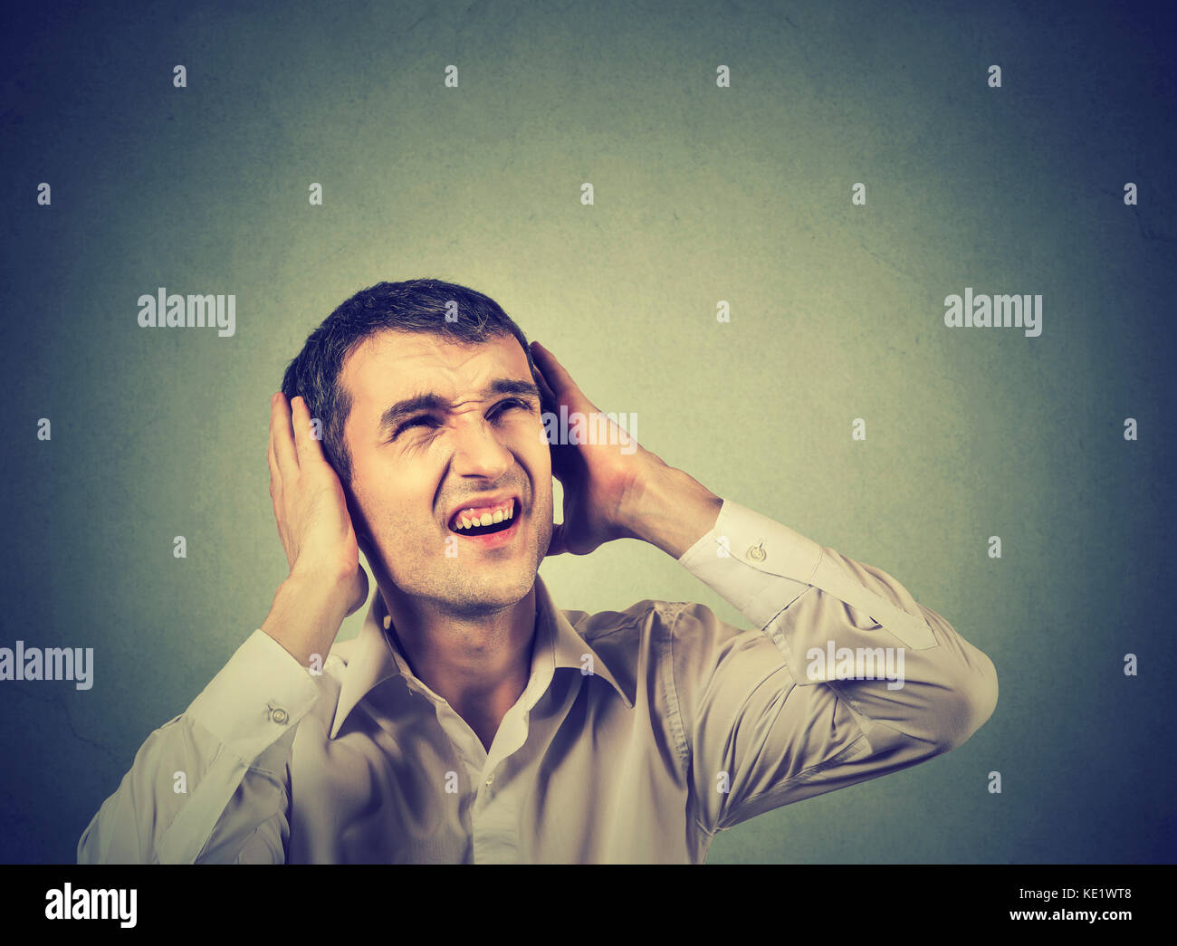 Young annoyed, unhappy, stressed man covering his ears, looking up ... Young annoyed, unhappy, stressed man covering his ears, looking up ...