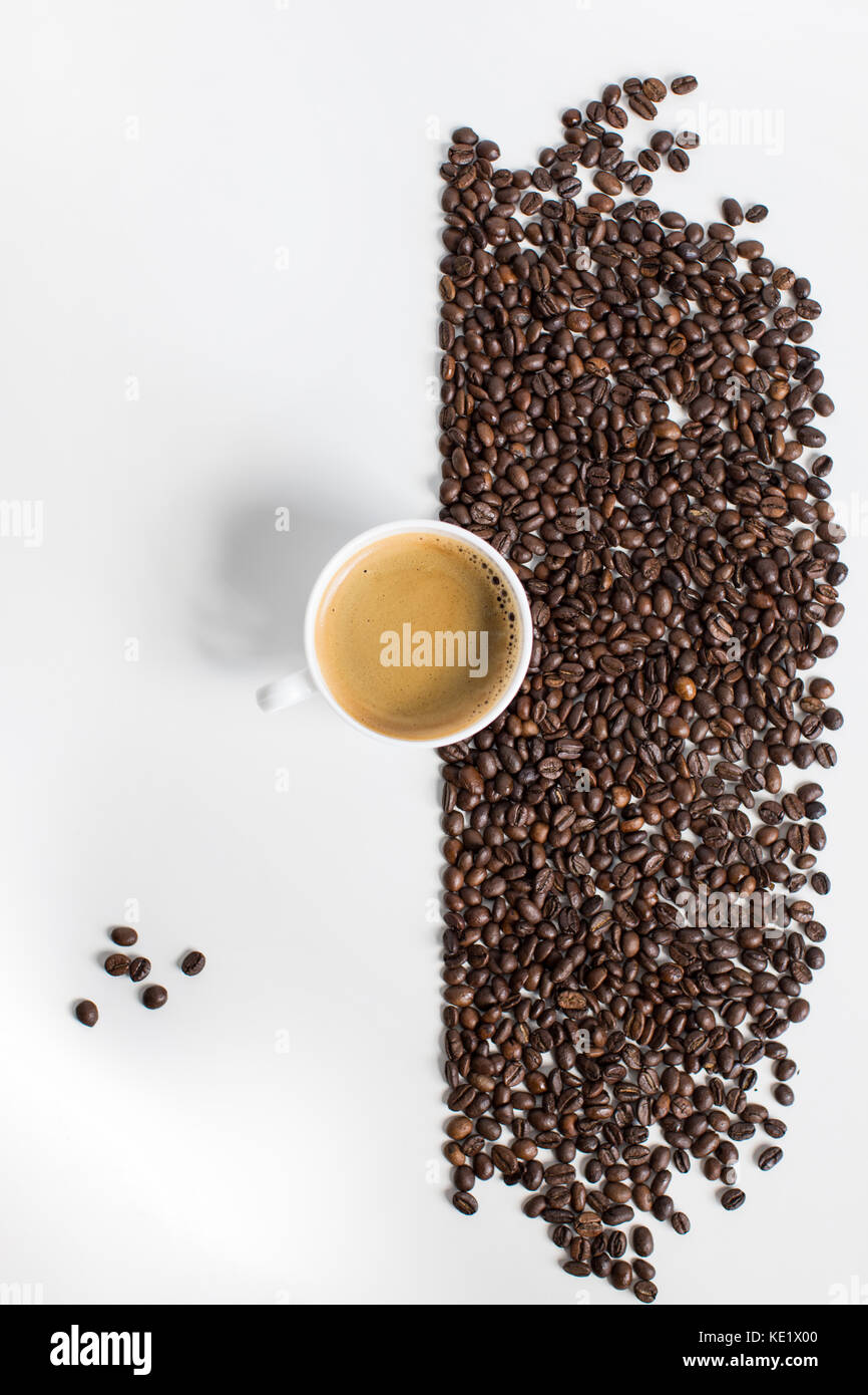 top view of cup of coffee and scattered coffee beans isolated on white ...