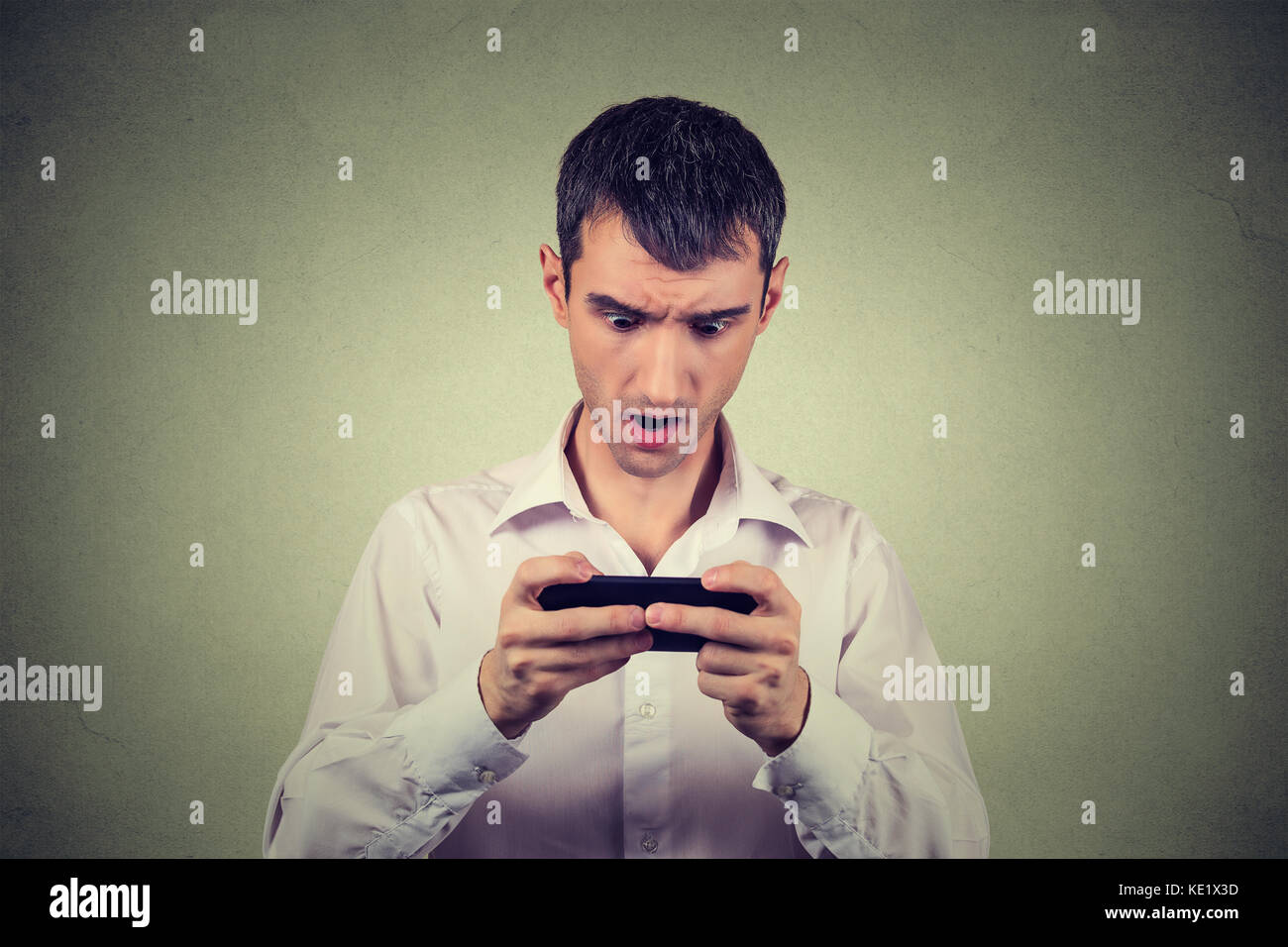 Closeup portrait anxious shocked young man looking at phone seeing bad ...