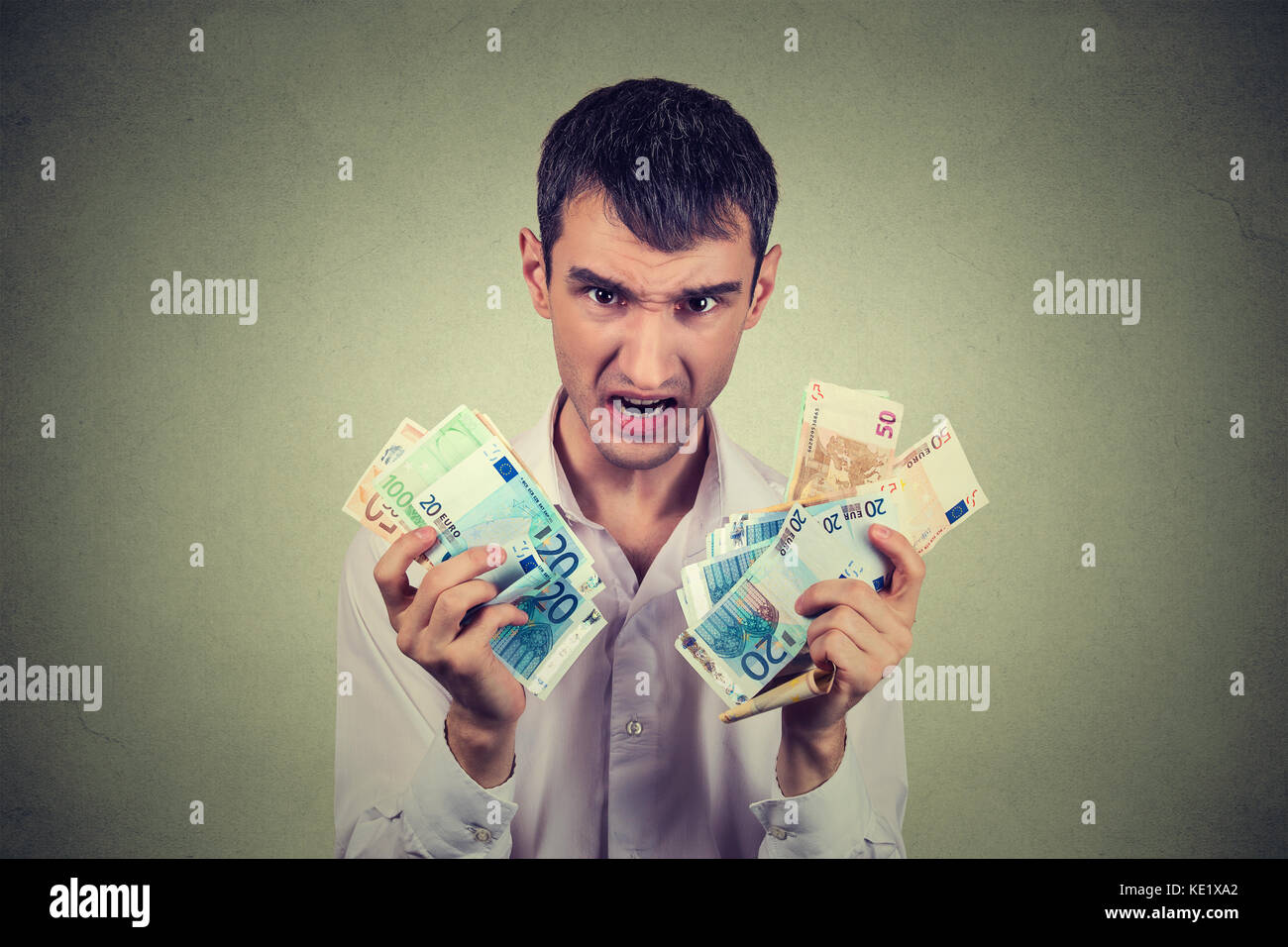 Greedy man with euro banknotes bills isolated on gray wall background ...