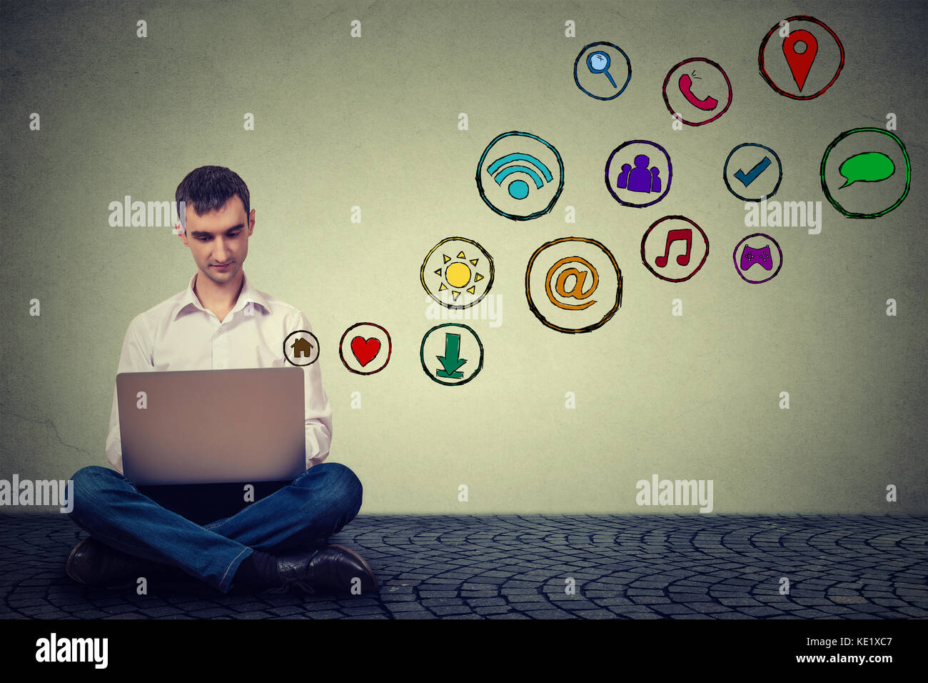 Young man working using laptop sitting on a floor social media ...