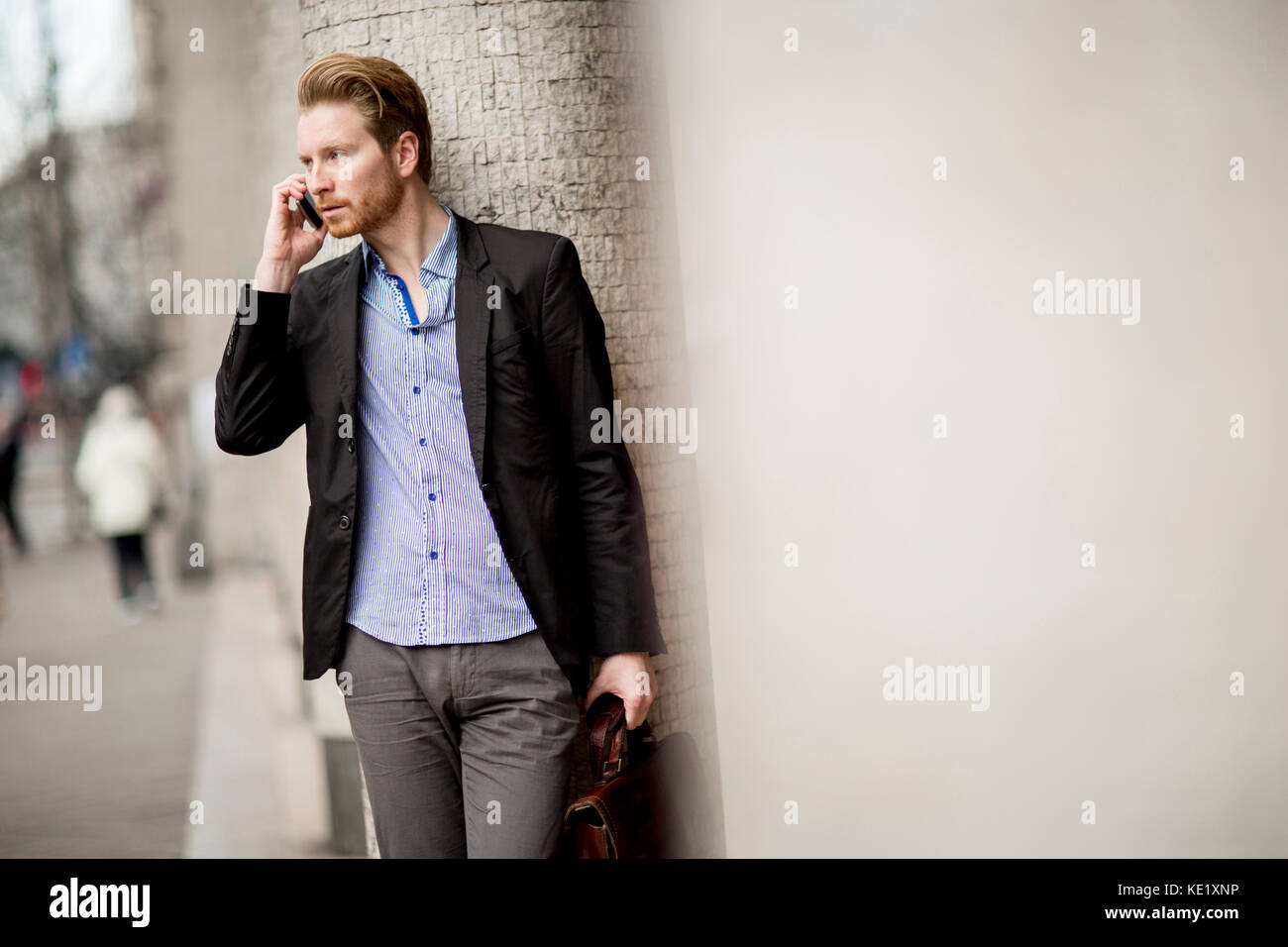 Portraite of ginger businessman waiting for transportation and using ...