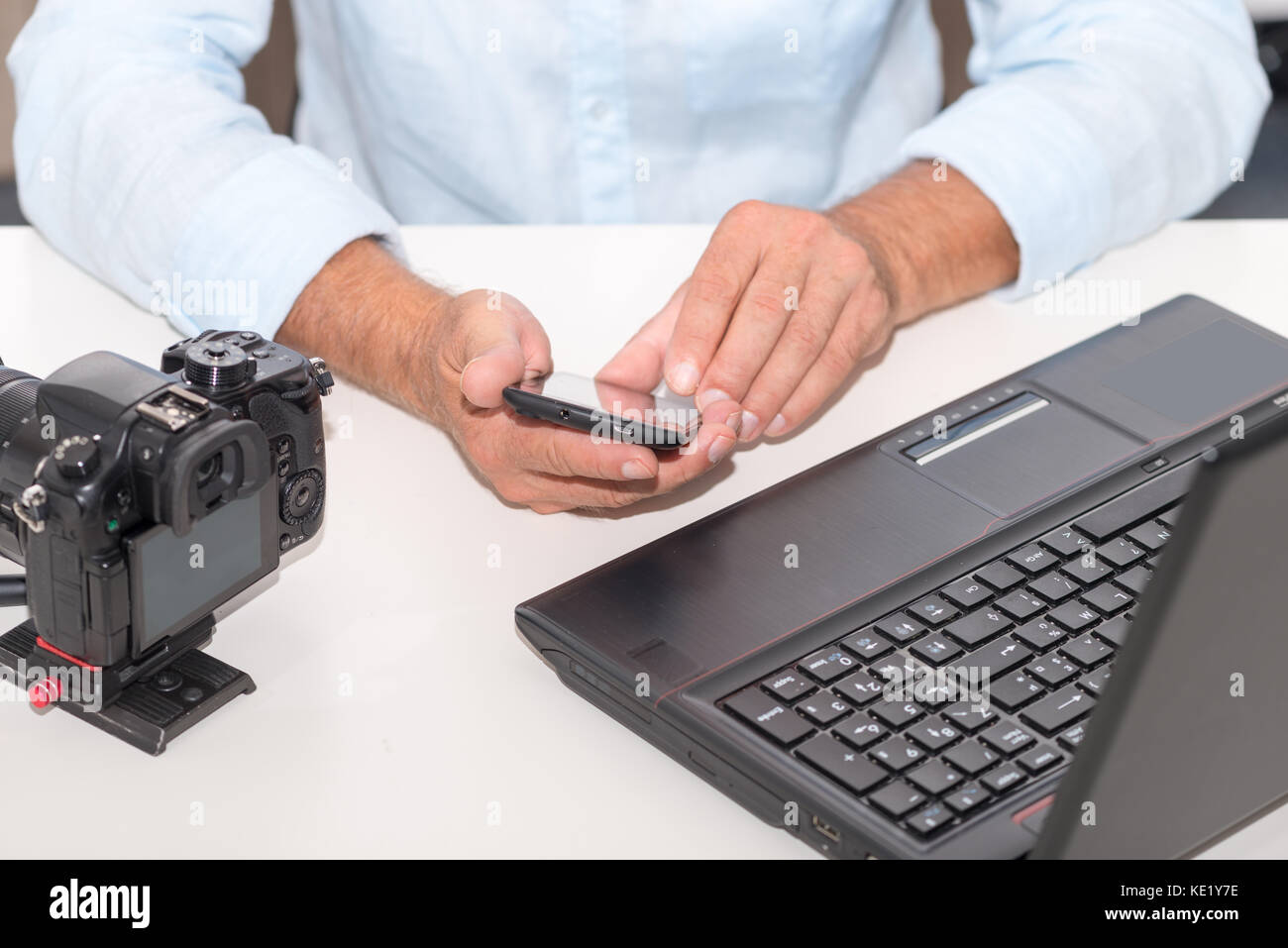 a photographer man using smartphone and laptop computer Stock Photo - Alamy