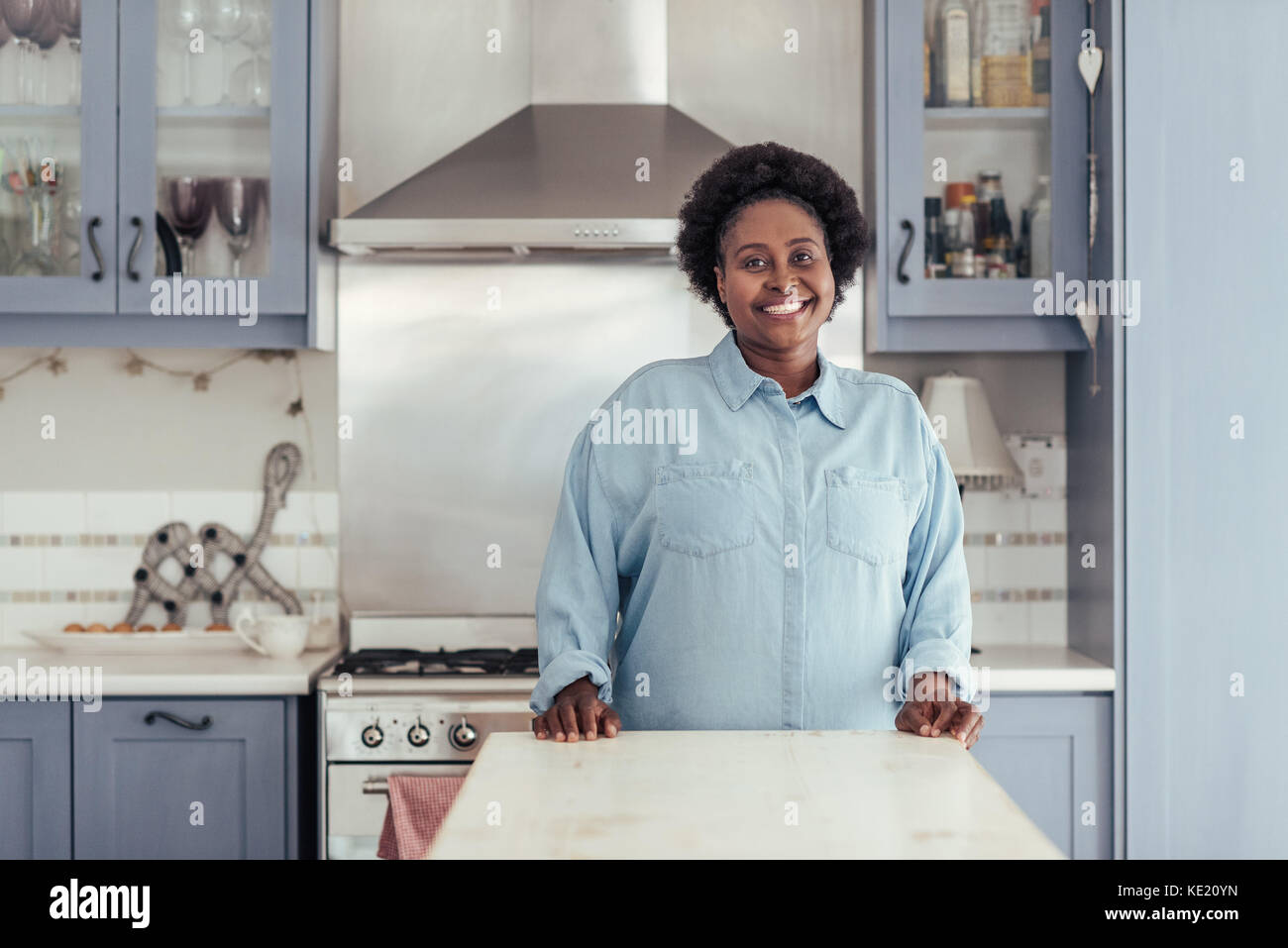 Content young African woman smiling while standing alone at a counter ...