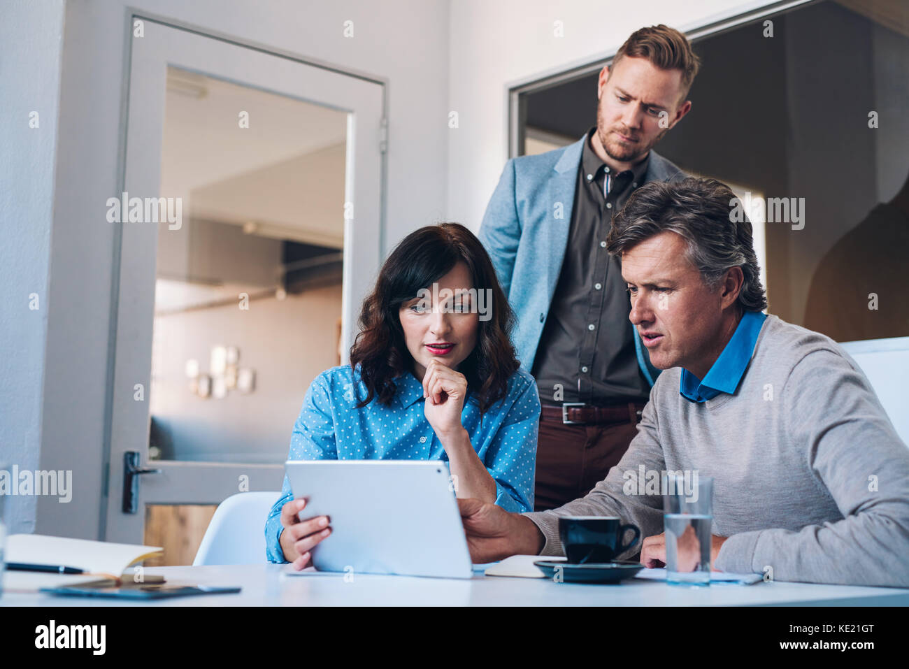 Young businessman talking with two work colleagues sitting at a table ...
