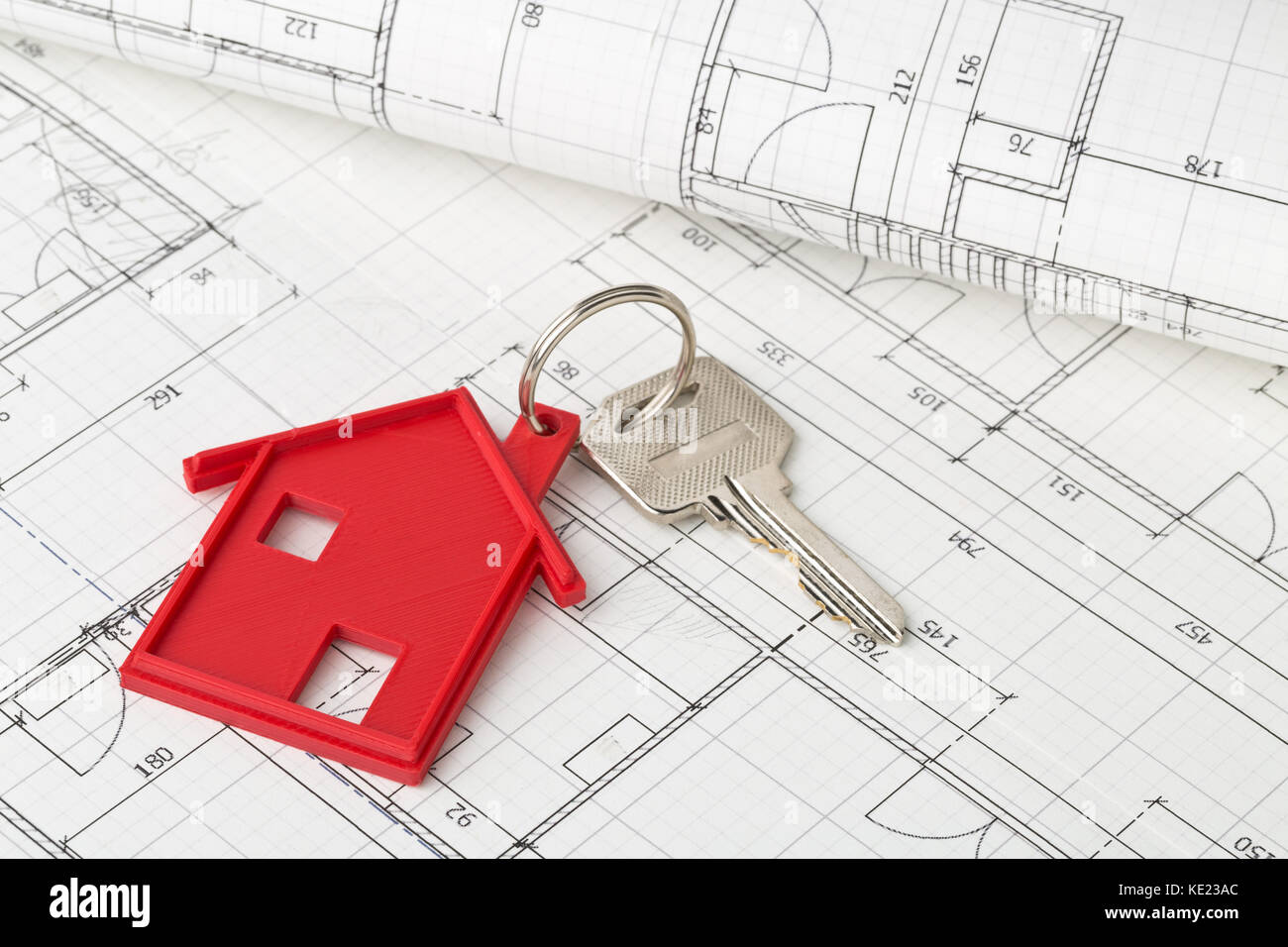 House door key with red house key chain pendant on building plans ...