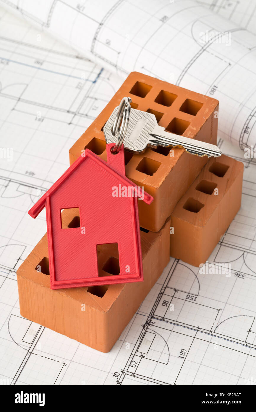 House door key with red house key chain pendant and bricks on building ...
