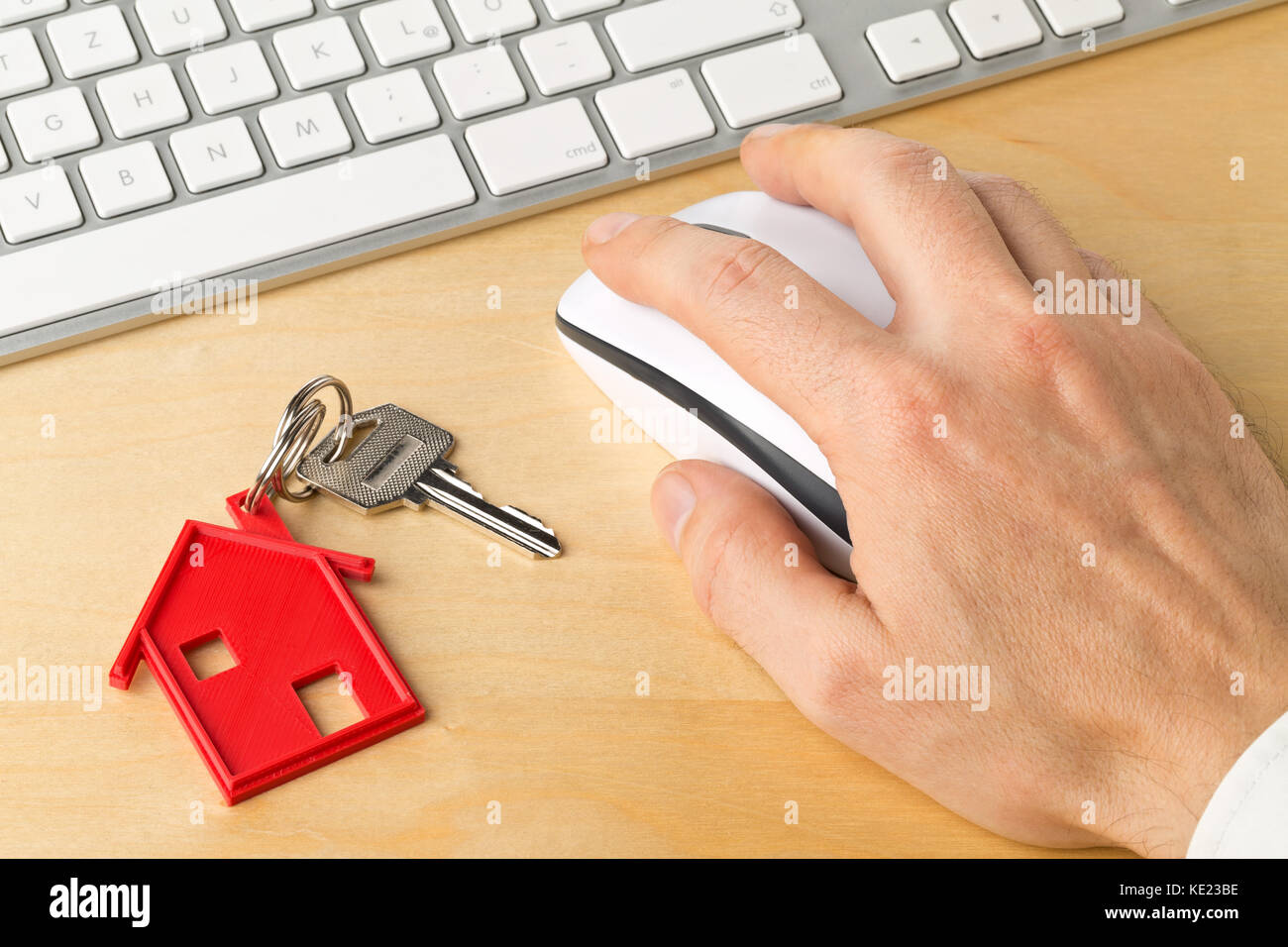 House door key with red house key chain pendant and man using computer ...