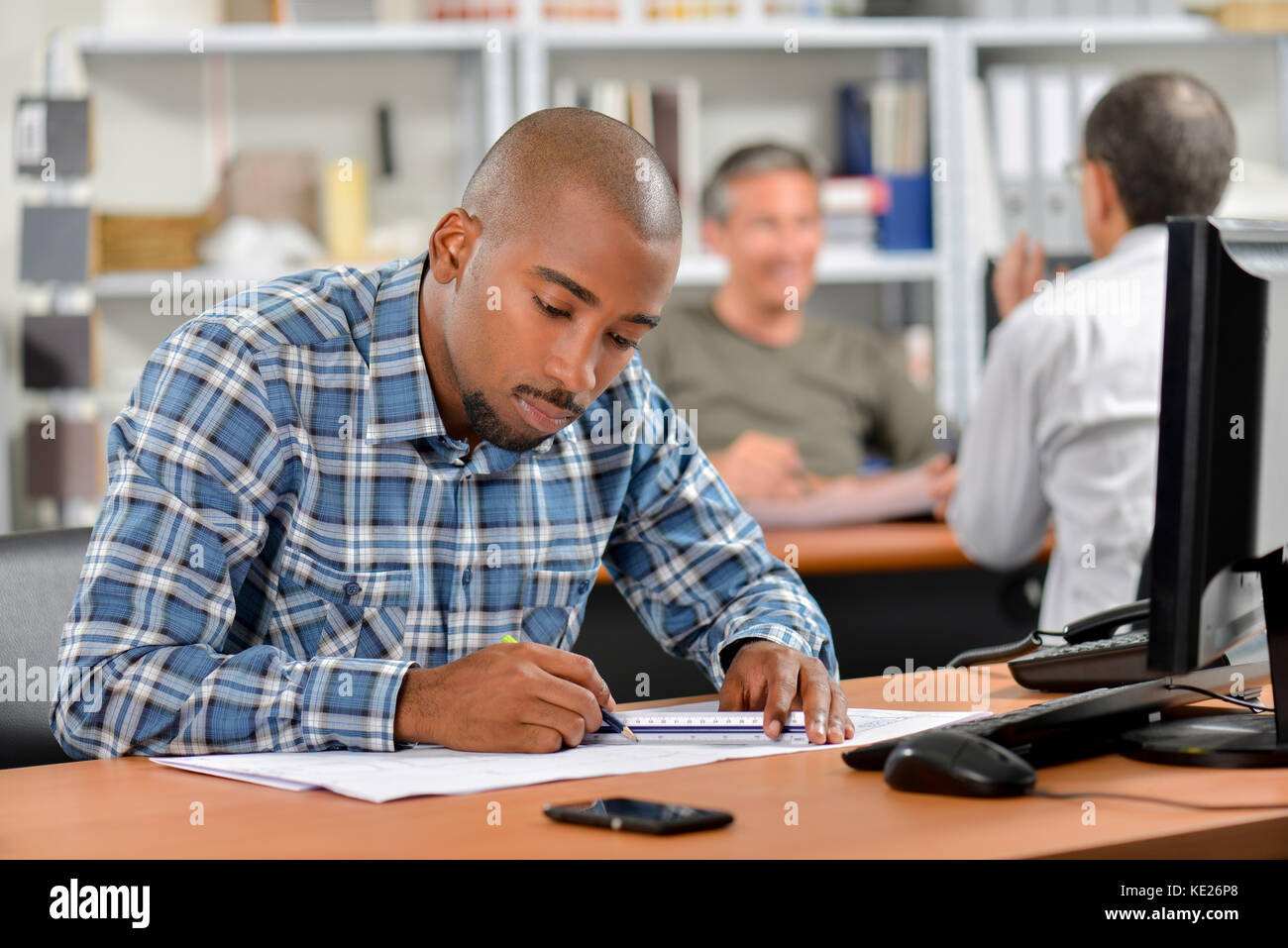 Man sat at desk working on blueprints Stock Photo - Alamy