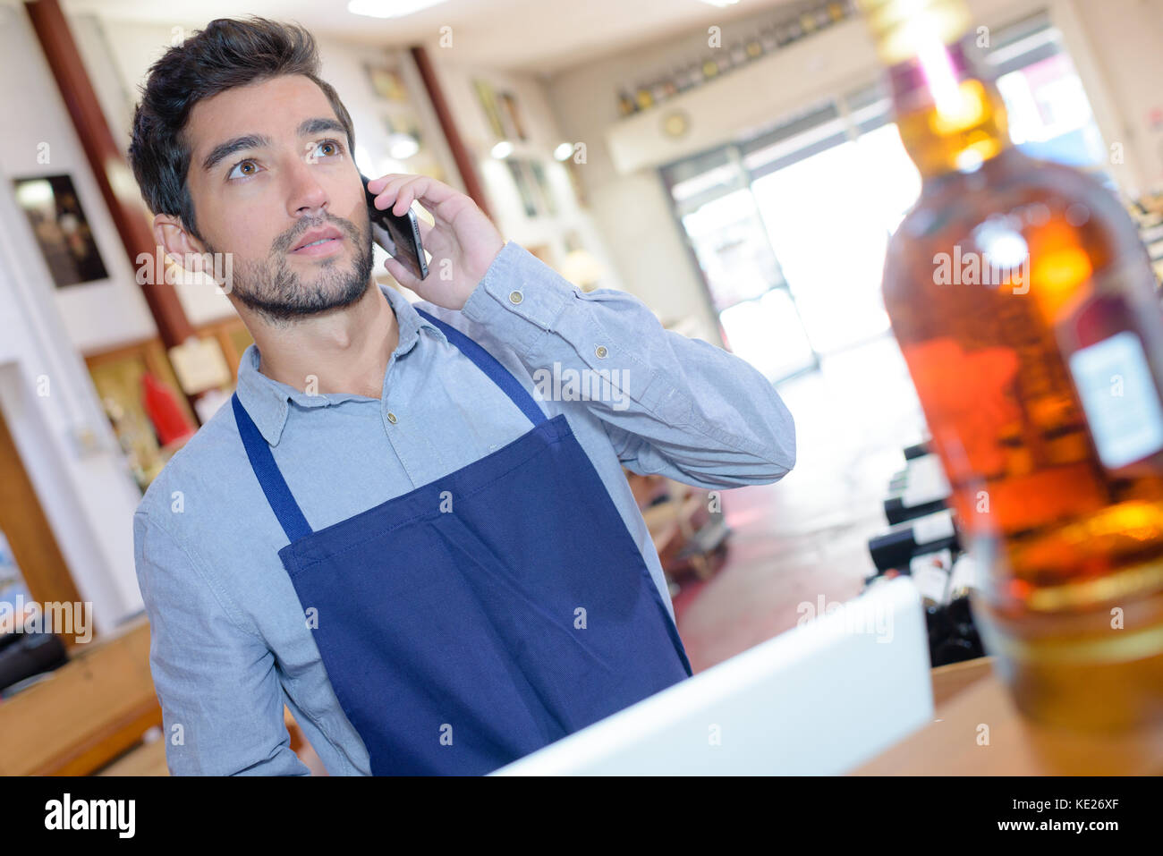 handsome salesman in apron on the phone Stock Photo - Alamy