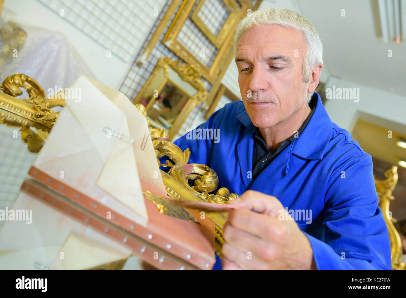 Man restoring mirror with gold leaf Stock Photo - Alamy