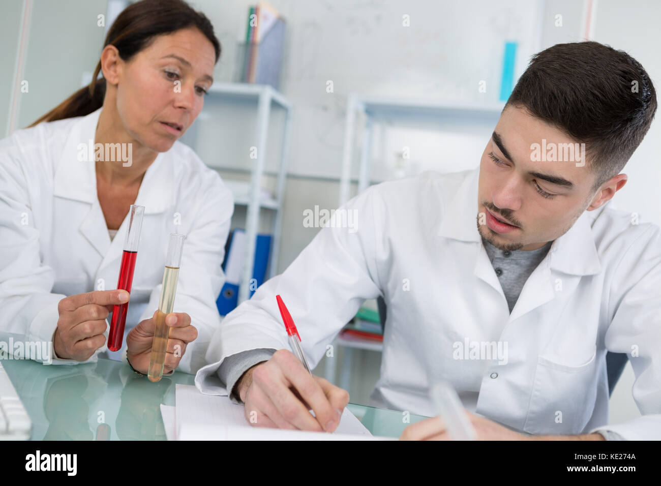 doctor holding red blood in test tube with apprentice Stock Photo - Alamy