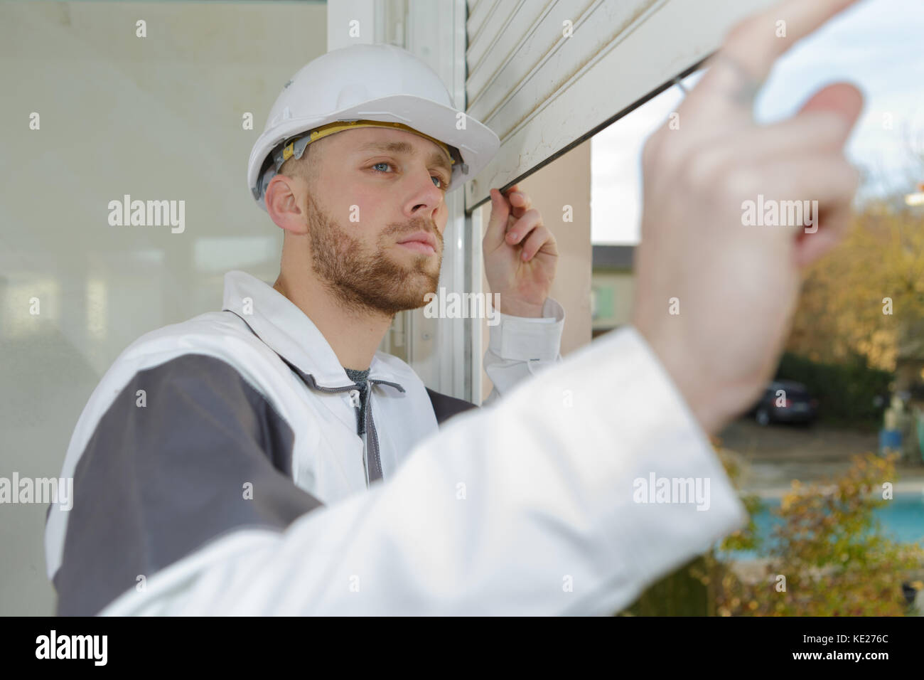 Contractor looking at window roller shutter Stock Photo - Alamy