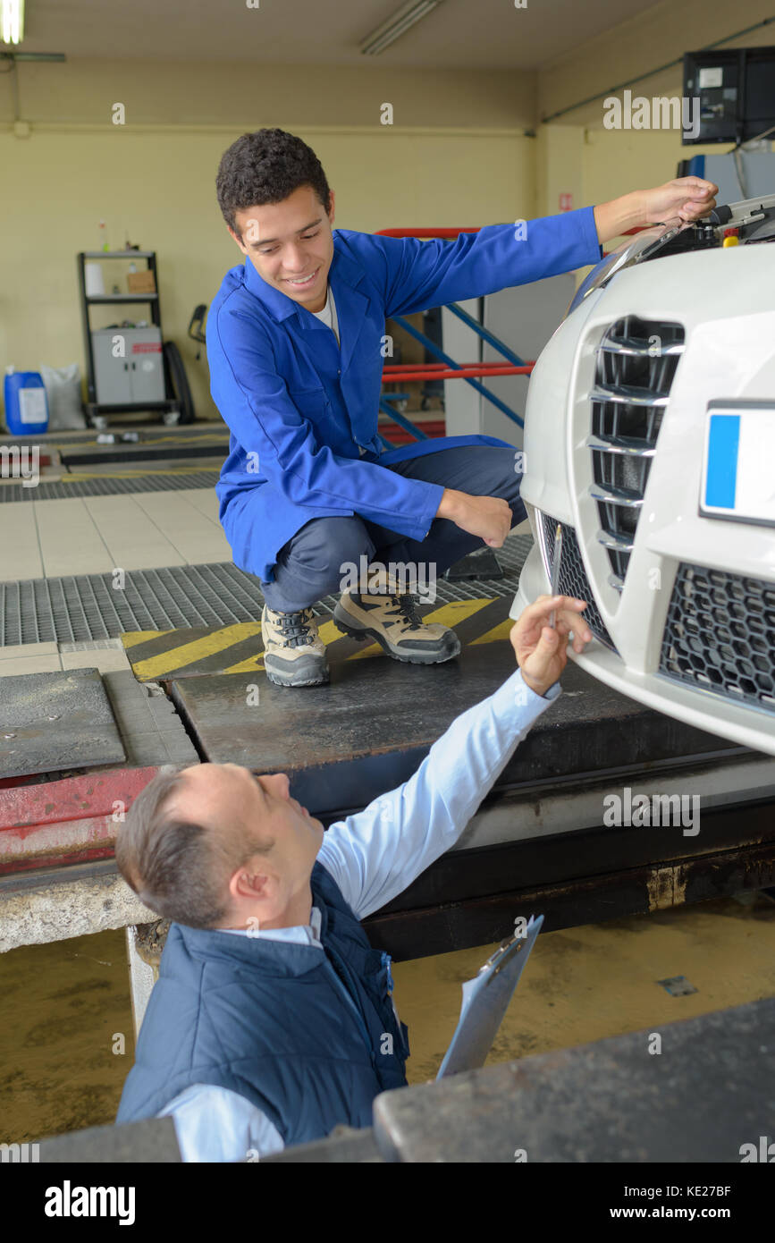 mechanics working on wheel underneath car Stock Photo - Alamy