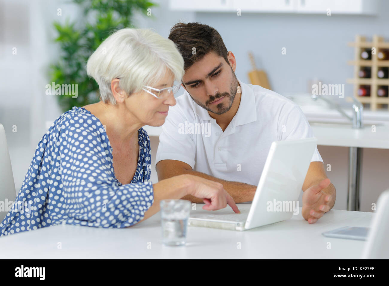Young man helping senior lady to use a laptop Stock Photo - Alamy