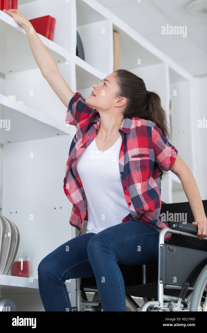 Woman in wheelchair struggling to reach something from shelf Stock ...