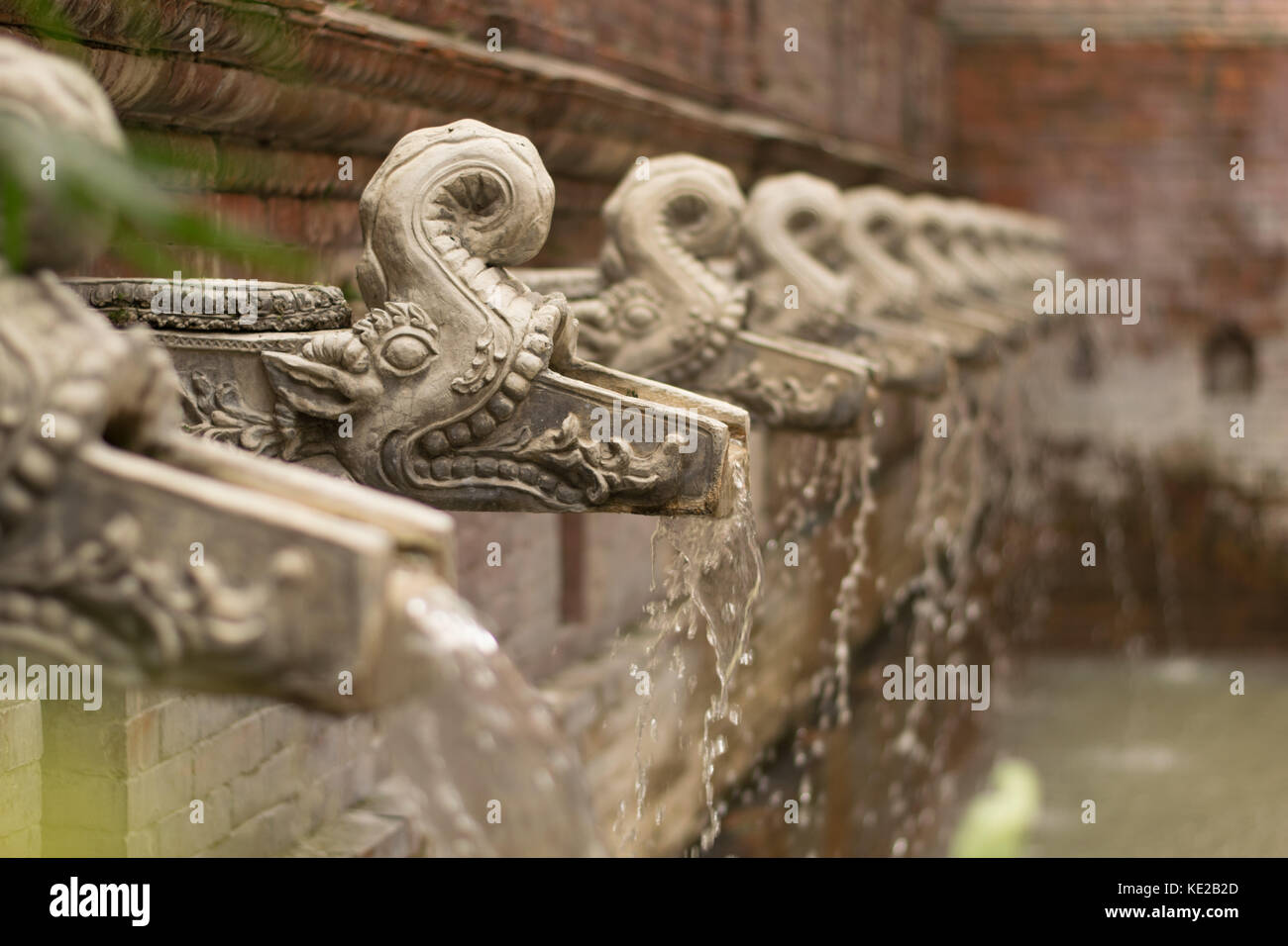 Traditional Nepali water taps shaped like gargoyles, filling a swimming ...