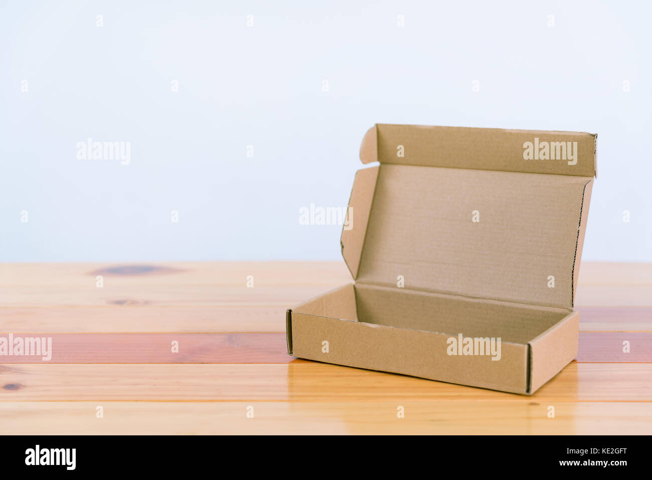 Empty brown cardboard box for mock up on bright wooden table with copy ...
