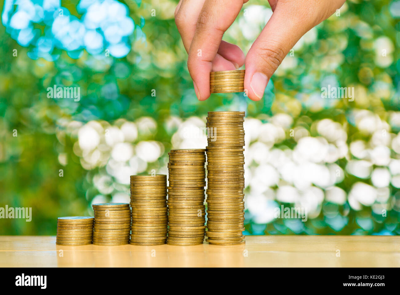 Woman hand put coin on step of coins stacks and gold coin money in the ...