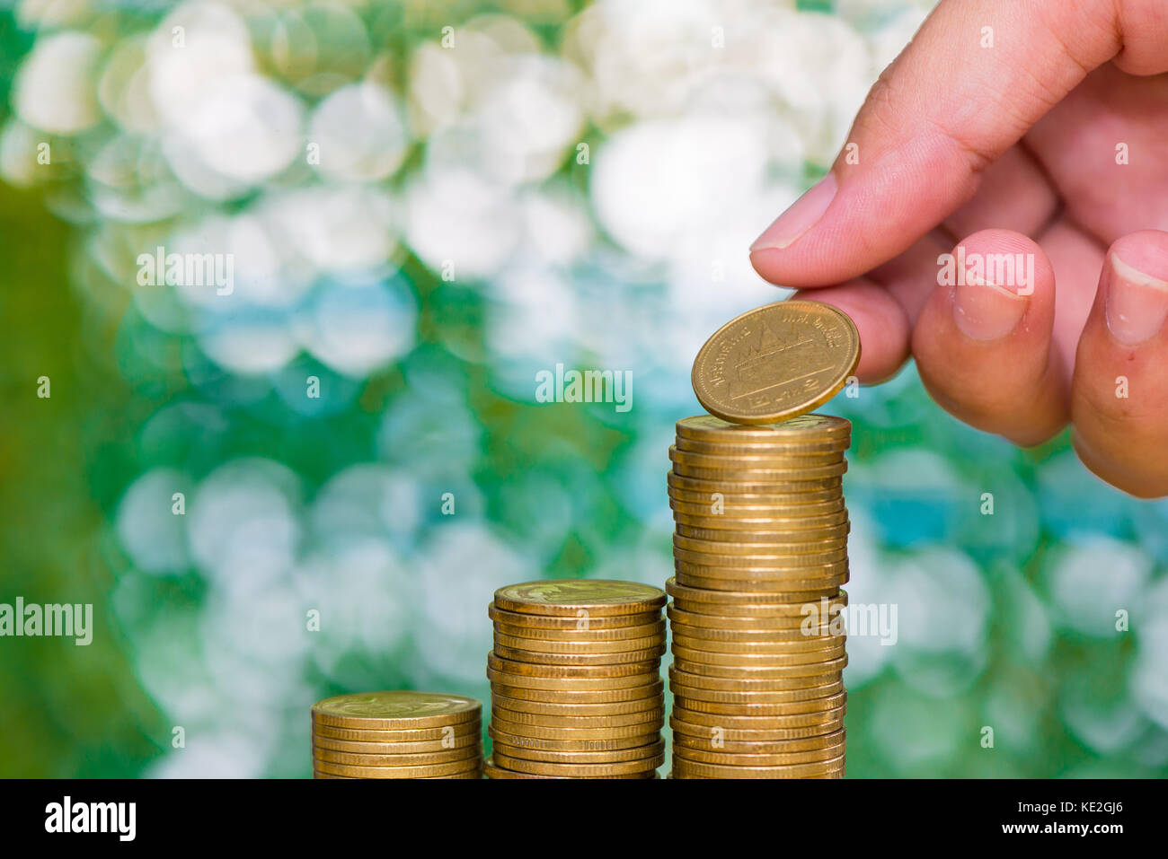 Woman hand put coin on step of coins stacks and gold coin money in the ...